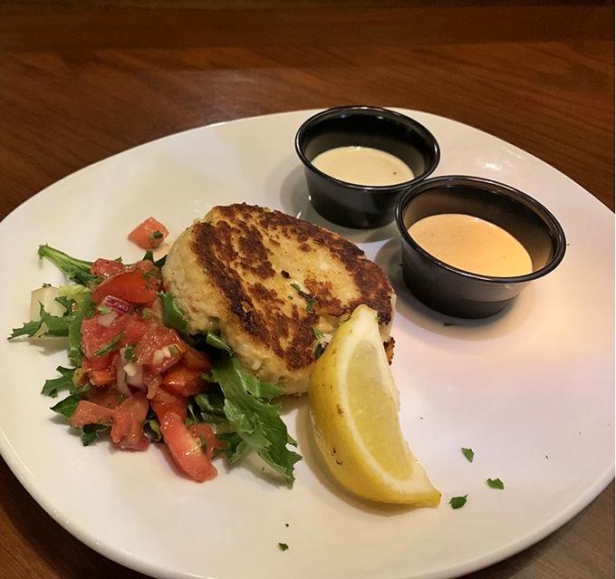 This crab cake isn't just golden—it's the Fort Knox of seafood starters. Two dipping sauces because important decisions shouldn't be forced upon you.