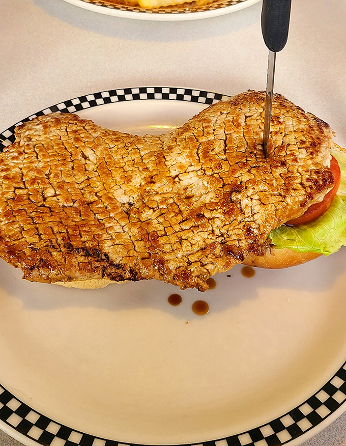 The breaded tenderloin – Indiana's unofficial state sandwich – extends well beyond its bun boundaries in a delicious act of culinary rebellion.