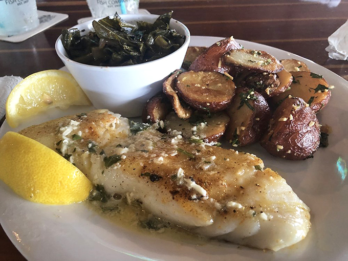 The chef's canvas in white. Perfectly seared fish bathed in garlic butter alongside roasted potatoes and collard greens—a Southern trinity of deliciousness.