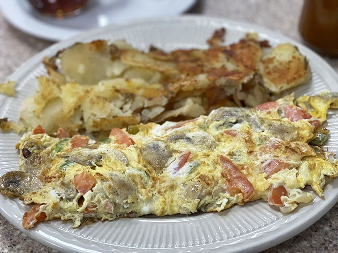 This isn't just any omelet—it's a vegetable sanctuary wrapped in perfectly cooked eggs. The hash browns deserve their own fan club.