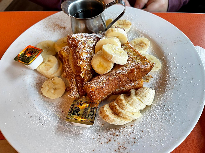 The Elvis would approve: French toast adorned with fresh bananas, powdered sugar, and what appears to be a splash of cinnamon—fit for The King himself.