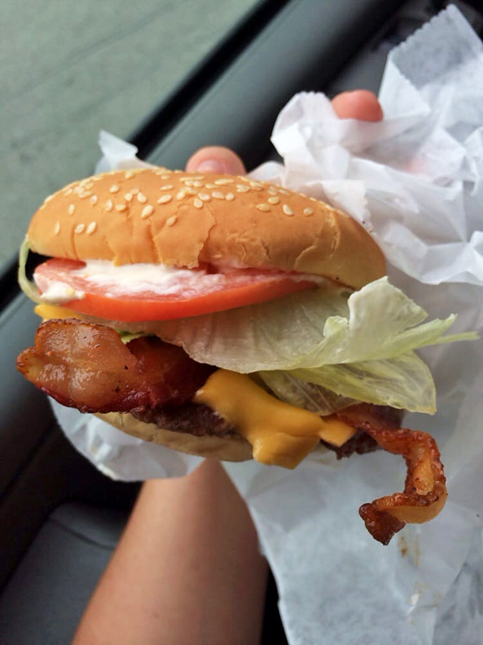 This isn't just a burger—it's edible architecture. Layers of melty cheese, crisp bacon, and fresh veggies create a masterpiece that requires both hands and several napkins.