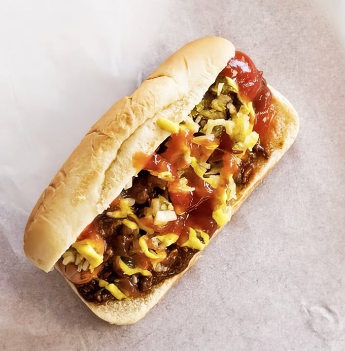 This isn't just a hot dog—it's a symphony of toppings performing on a perfectly grilled stage, with ketchup and mustard providing the colorful finale.