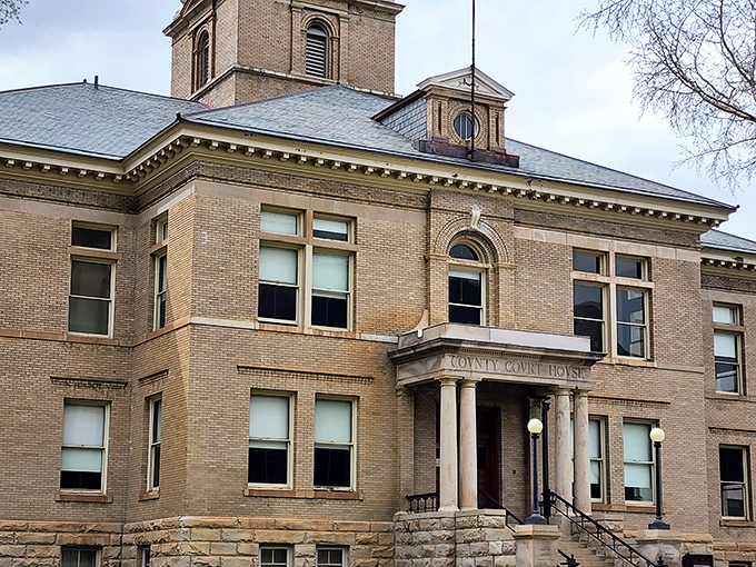 The courthouse stands like a dignified elder statesman, silently judging modern architecture with its timeless brick elegance.