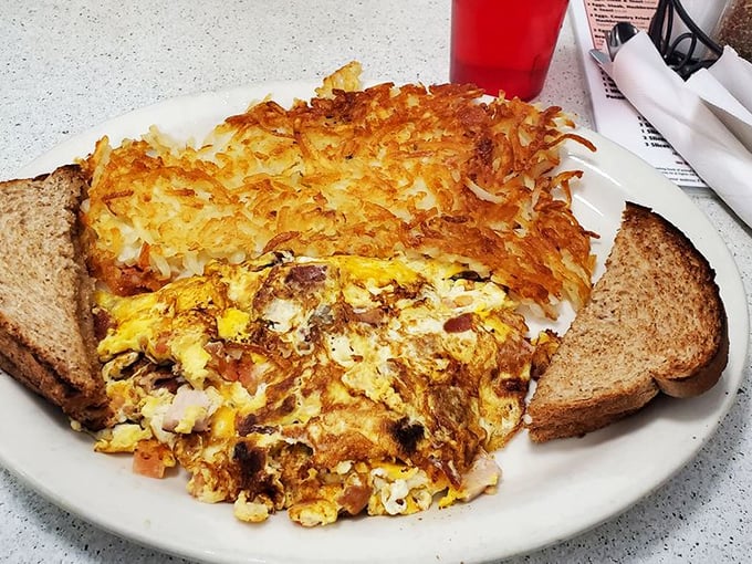 This isn't just an omelet – it's a masterclass in breakfast architecture with crispy hash browns standing guard like delicious sentinels.