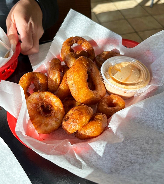 Golden-fried onion rings with that perfect crunch factor. The dipping sauce isn't just an accessory – it's an essential supporting character.