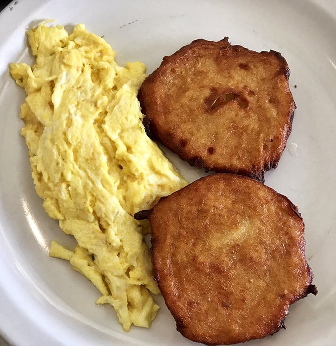 The breakfast duet that never misses a note—fluffy scrambled eggs alongside crispy potato pancakes that crackle with each forkful.