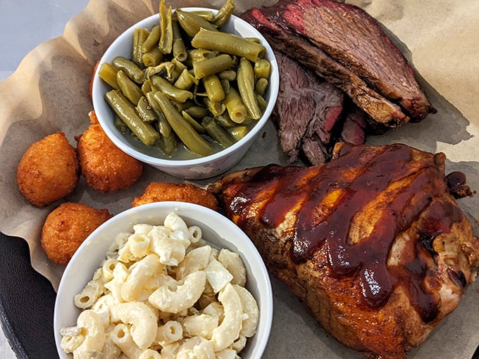A barbecue platter that belongs in the Louvre—mac and cheese that's actually worthy of the meat, green beans that haven't surrendered all dignity, and chicken wearing sauce like a designer outfit.