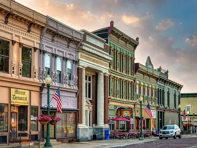 Downtown Mount Carroll at golden hour—where American flags flutter above brick streets, and storefronts glow with the patina of genuine history.