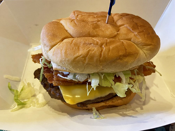 A burger that requires jaw exercises beforehand – layers of bacon, cheese, and fresh veggies stacked higher than your weekend to-do list.