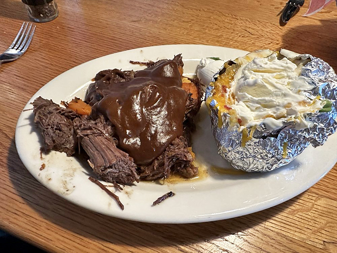 Pot roast swimming in rich gravy alongside a foil-wrapped potato. When food looks this homey, you know someone's grandmother would approve.