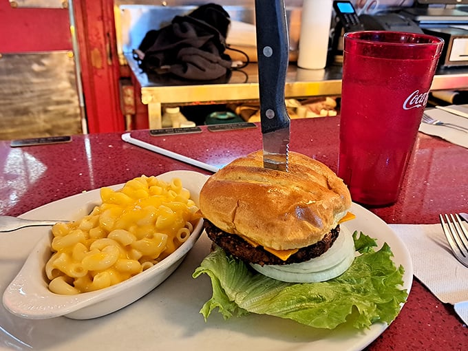 This burger doesn't just sit on the plate—it commands attention, flanked by mac and cheese that's unapologetically yellow and gloriously comforting.