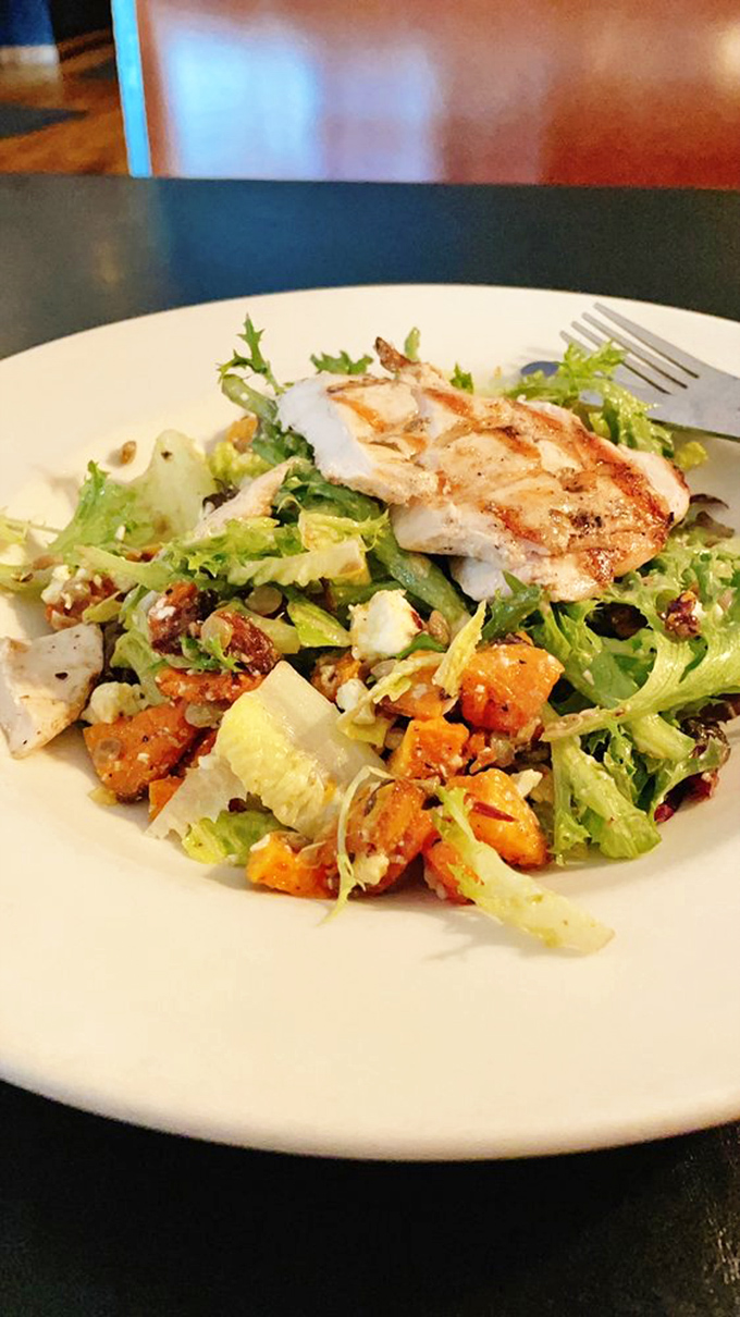 A salad that doesn't apologize for being delicious – grilled chicken atop fresh greens with roasted butternut squash and tangy dressing.
