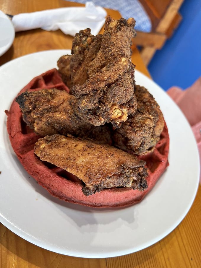 Red velvet waffle meets perfectly seasoned chicken—a marriage of flavors that would make even breakfast skeptics set early alarms.