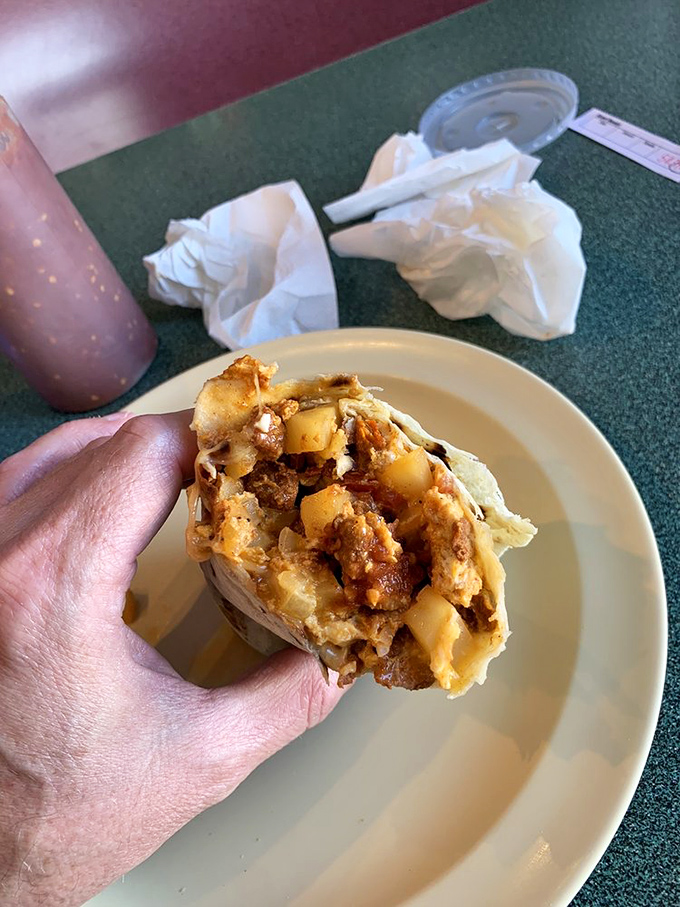 That sandwich in the background is merely a spectator to the real star – a burrito so gloriously smothered it requires strategic planning before the first bite.