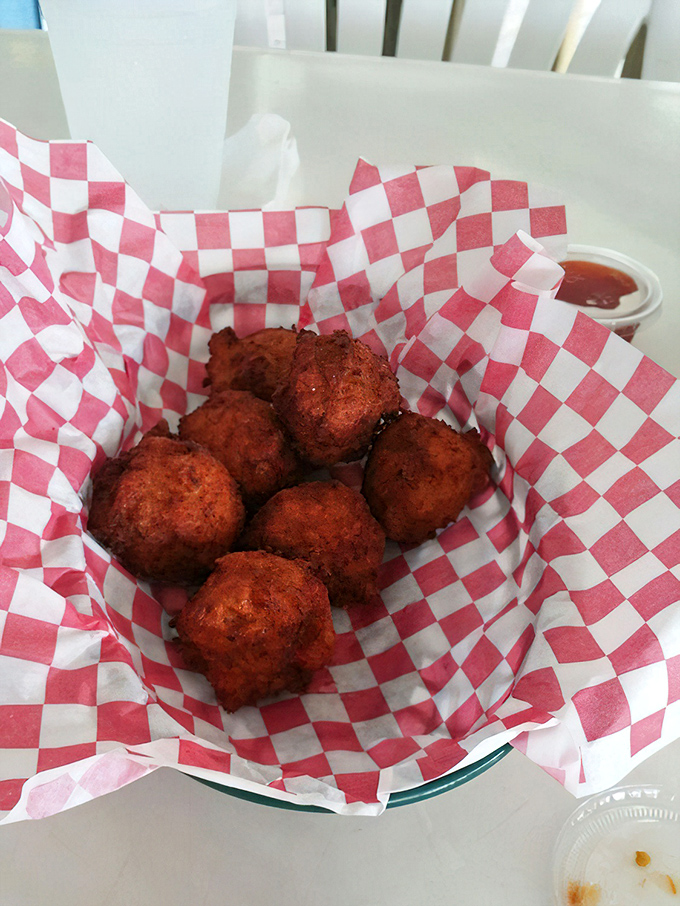 Golden hushpuppies nestled in checkered paper—little orbs of cornmeal joy that make you wonder why you don't eat these every single day.
