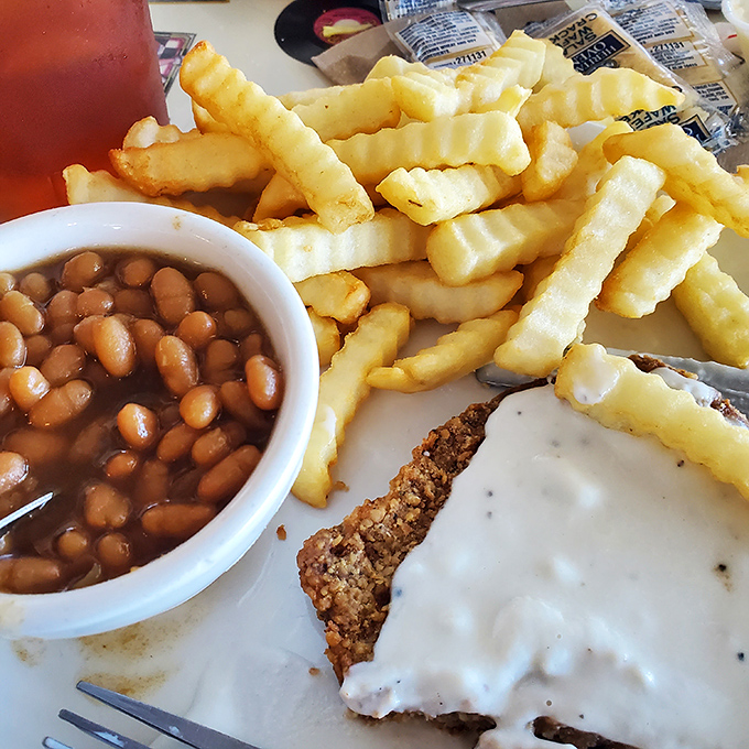 Country fried steak with a side of nostalgia. Those crinkle-cut fries and beans aren't just sides—they're essential characters in this comfort food story.