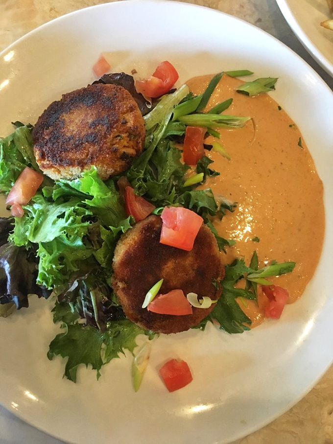 Behold the legendary crab cakes that inspire road trips – golden beauties nestled on greens like edible treasure chests.
