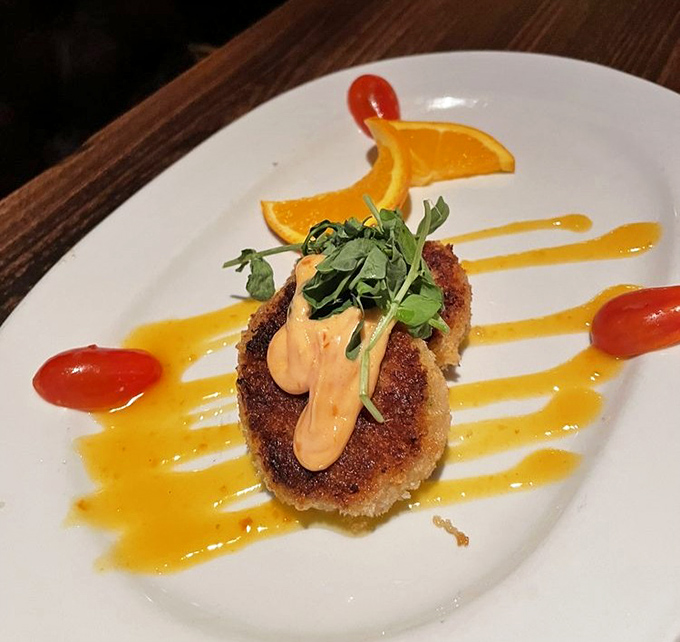 This isn't just a crab cake—it's a golden disk of oceanic joy, dressed for success with colorful sauces and a jaunty microgreen hat.