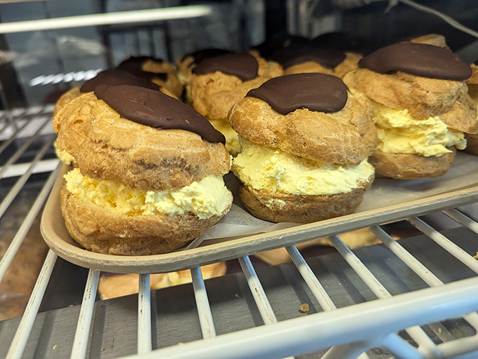 Cream puffs wearing chocolate hats and looking mighty pleased about it. These little giants are what pastry dreams are made of.