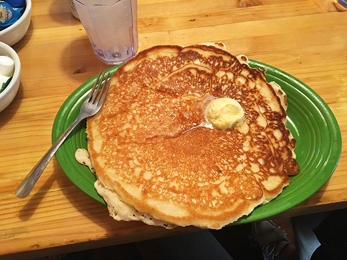 The pancake arrives like a golden disc of morning sunshine, with a pat of butter slowly melting into its fluffy depths.