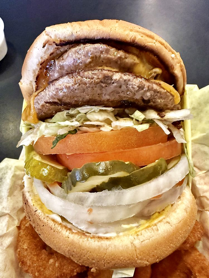 Behold the double cheeseburger in its natural habitat – a towering monument to excess that somehow maintains perfect structural integrity with each glorious bite.