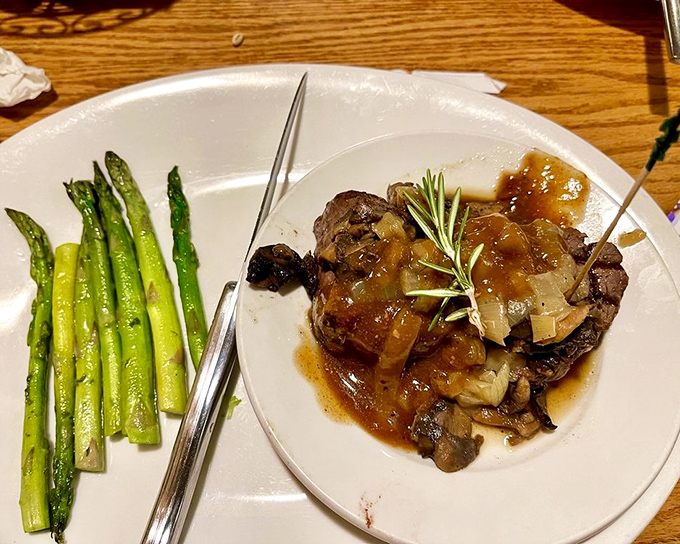 A filet mignon bathed in rich sauce, standing tall like a meaty monument to culinary excellence. Those asparagus spears aren't just garnish—they're witnesses to greatness.