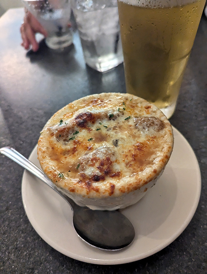 French onion soup done right—a bubbling cauldron of sweet onions and savory broth under a golden cheese canopy. Spoon-breaking good.
