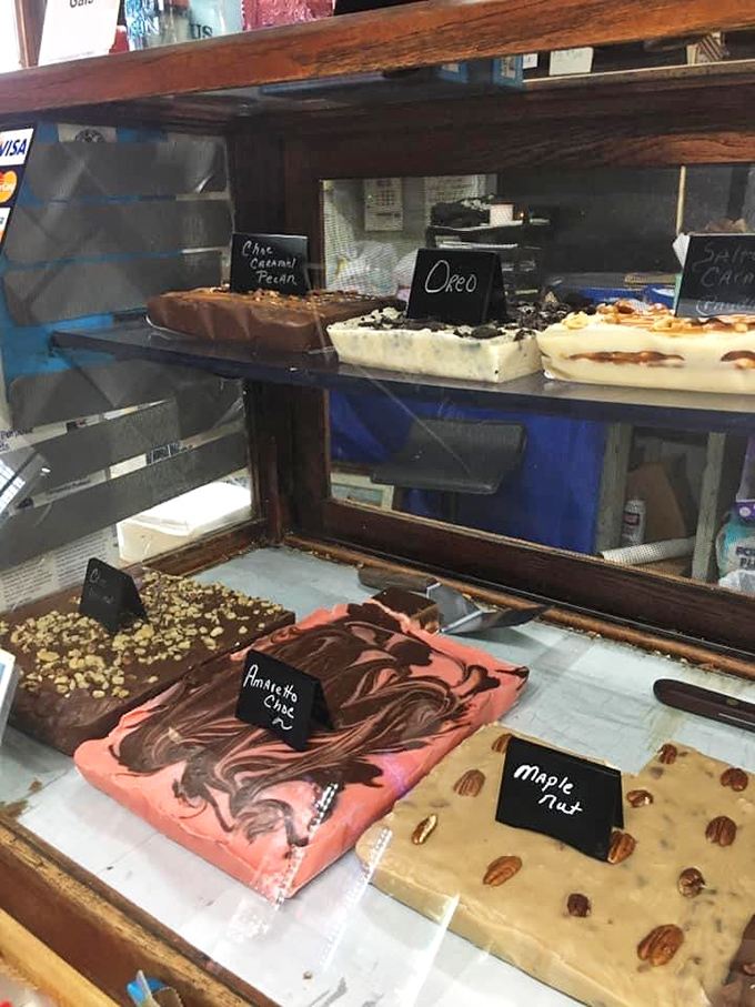 The fudge display case—where chocolate, peanut butter, and maple nut squares wait patiently like contestants in the world's most delicious beauty pageant.