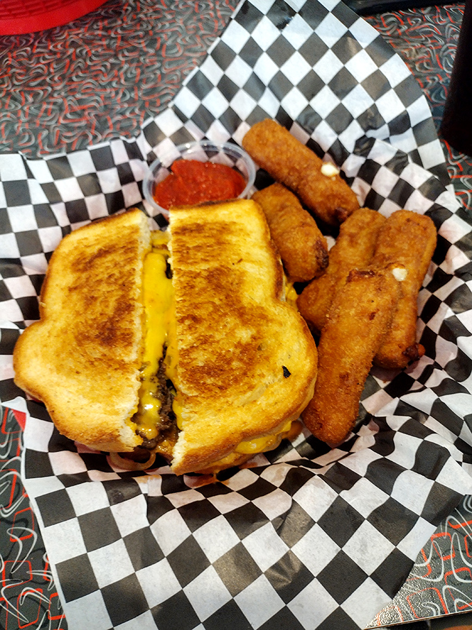 The humble grilled cheese elevated to art form—golden, crispy exterior giving way to that perfect cheese pull, with a side of golden mozzarella sticks for good measure.