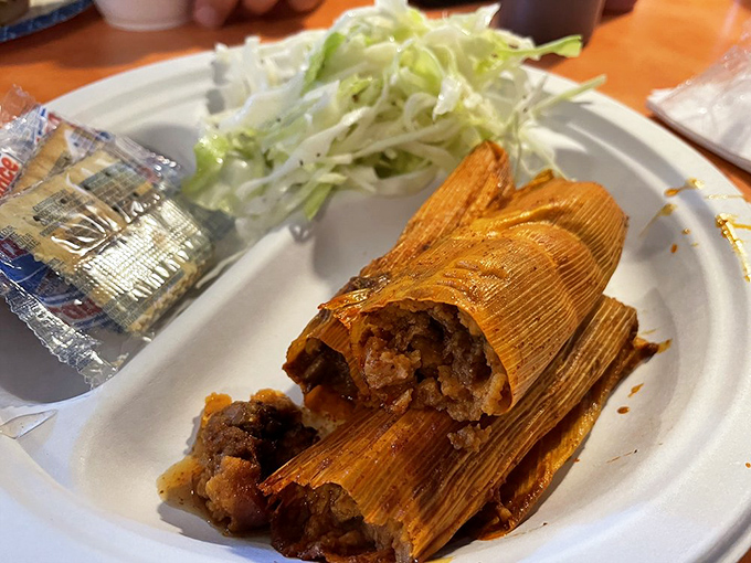 Delta tamales—corn husks unfurling to reveal spiced treasures within—served with a side of slaw that cuts through the richness perfectly.