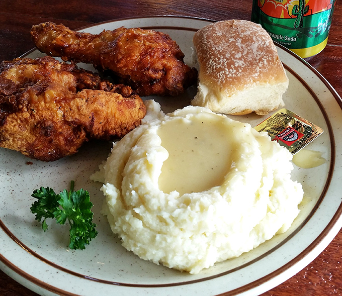 The holy trinity of comfort: crispy fried chicken, cloud-like mashed potatoes with a gravy lake, and a roll for sopping up every last bit.