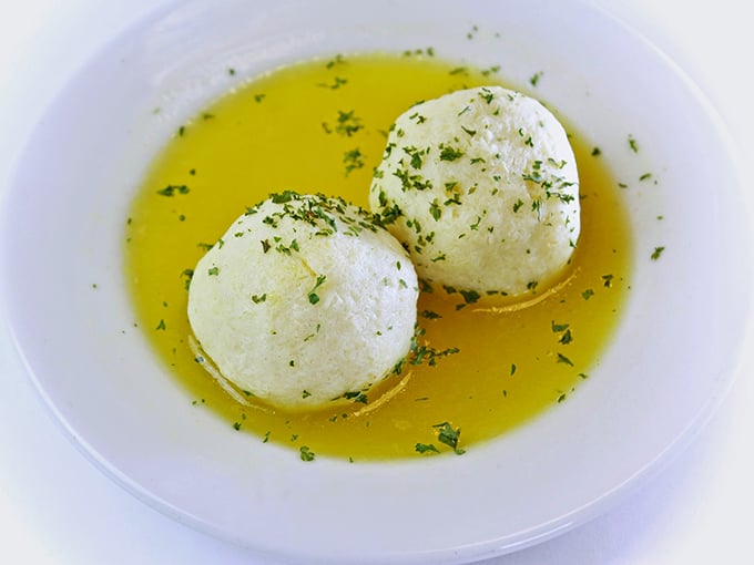 These matzo balls float like clouds in golden broth—the Jewish penicillin that could cure everything from colds to existential crises.