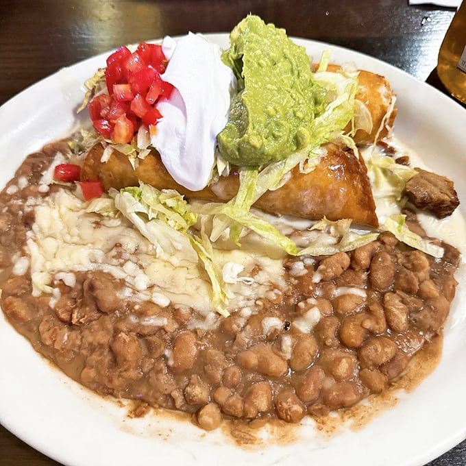 A fiesta on a plate! Rice, beans, and a crispy chimichanga topped with all the fixings create a symphony of textures that'll have your taste buds dancing the jarabe tapatío.