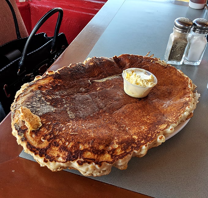 The pancake that ate Wickenburg! This golden-brown behemoth doesn't just hang over the edge of the plate—it conquers it completely.