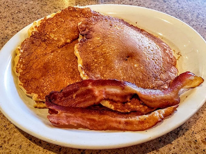 Golden pancakes and bacon strips arranged with the casual confidence of a diner that knows exactly what Sunday morning salvation looks like.