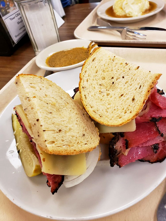 A sandwich so substantial it requires strategic planning for that first bite—layers of pastrami and Swiss on rye that make fast food chains hang their heads in shame.
