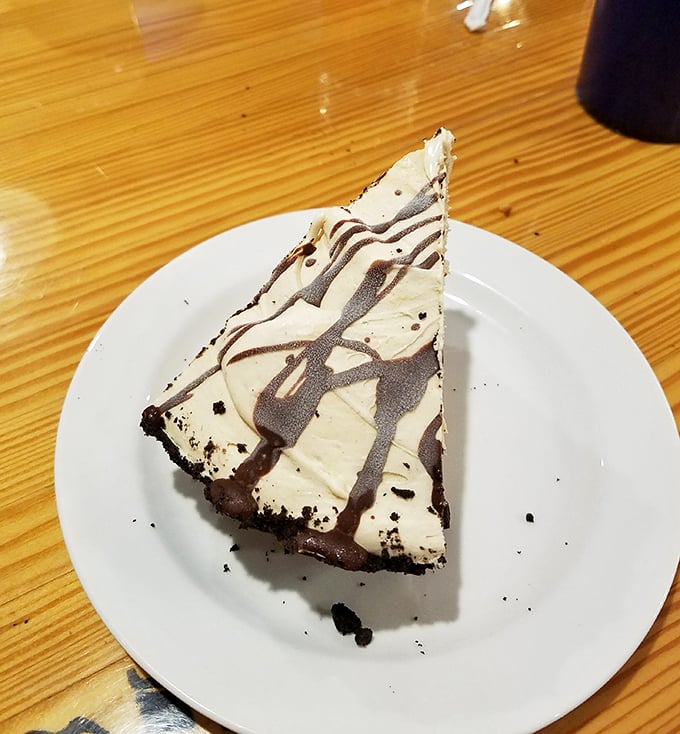 Dessert architecture at its finest—a slice of chocolate-drizzled pie that makes you contemplate ordering a second piece before finishing the first.