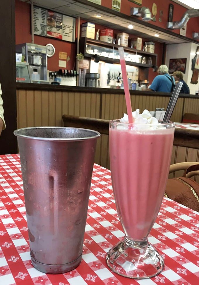 The strawberry shake arrives like a pink tower of possibility, its frosty metal companion standing by for seconds—because there will be seconds.