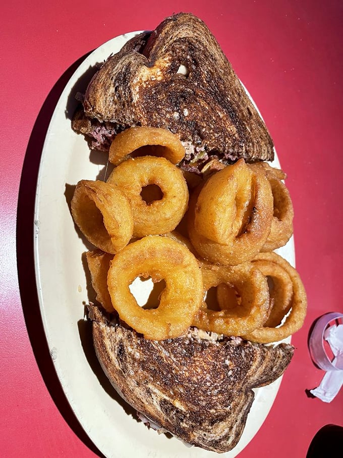 The sandwich centerfold: melted cheese peeking out between marble rye, surrounded by a supporting cast of golden onion rings. Food photographers, take notes.
