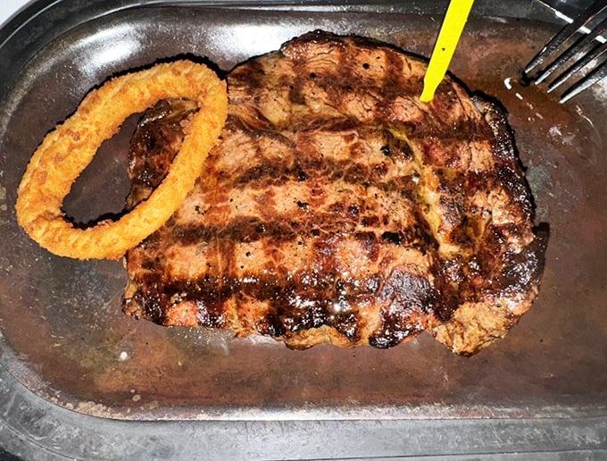 A ribeye with perfect grill marks and an onion ring companion—like Batman and Robin, if they were delicious and made you happier than any superhero.