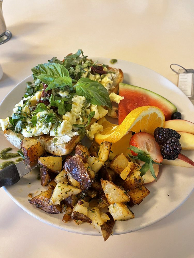 Breakfast artistry at its finest—eggs, fresh herbs, and perfectly roasted potatoes sharing space with fruit that looks hand-selected by Mother Nature herself.