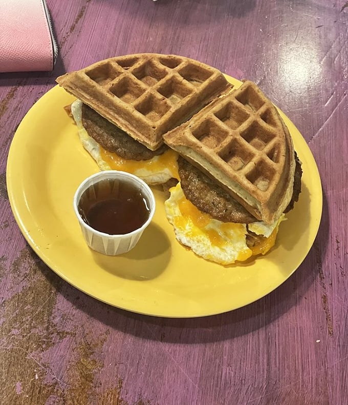 Waffle sandwich architecture at its finest – crispy exterior, fluffy interior, with eggs and sausage creating the ultimate breakfast skyscraper.