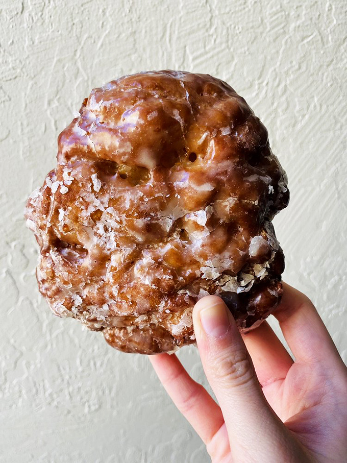 This apple fritter isn't just a donut – it's a craggy, caramelized mountain range of sweet satisfaction dusted with crystal sugar snow.