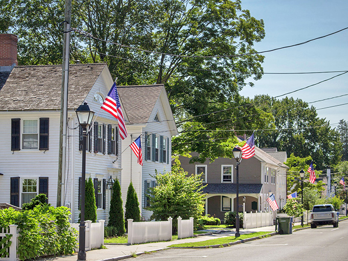 American flags flutter along tree-lined streets where Revolutionary War soldiers once marched. Some towns preserve history; Essex lives inside it.