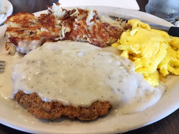 Country-fried steak swimming in peppery gravy alongside crispy hash browns—comfort food that hugs your soul before noon.