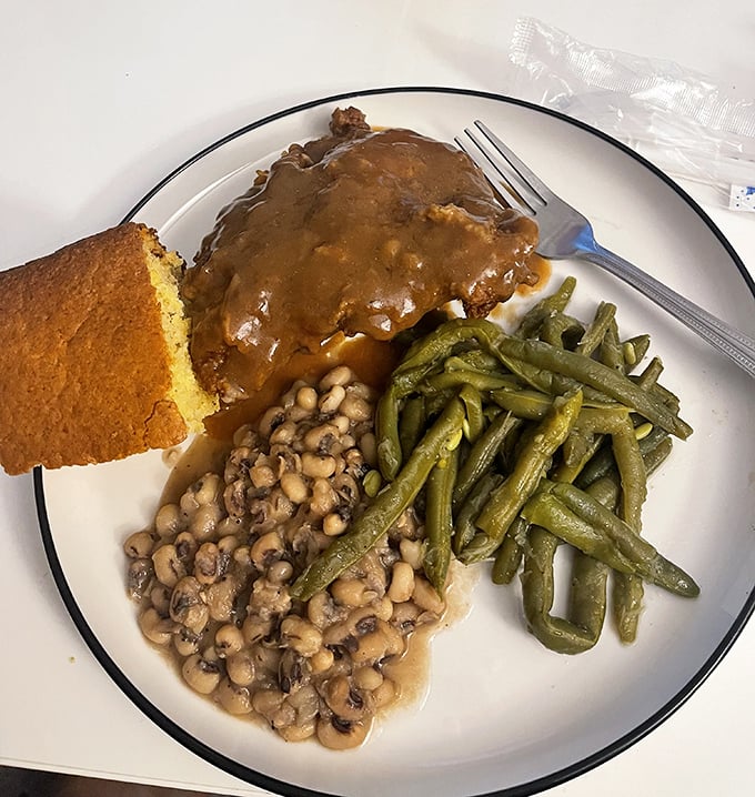 Soul on a plate—smothered goodness swimming in gravy alongside black-eyed peas and green beans that would make your grandmother nod in approval.