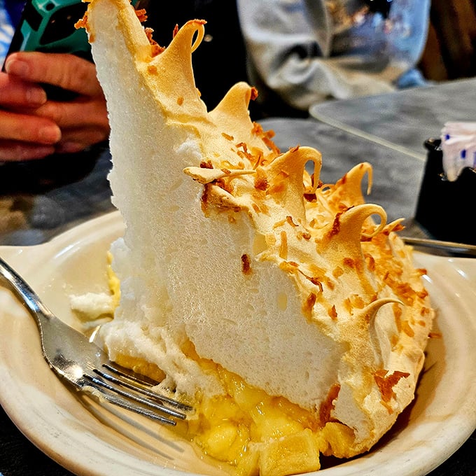 Not just pie—it's architecture. That impossibly tall meringue defying gravity while hiding pockets of sunshine below. Fork required, sharing optional.