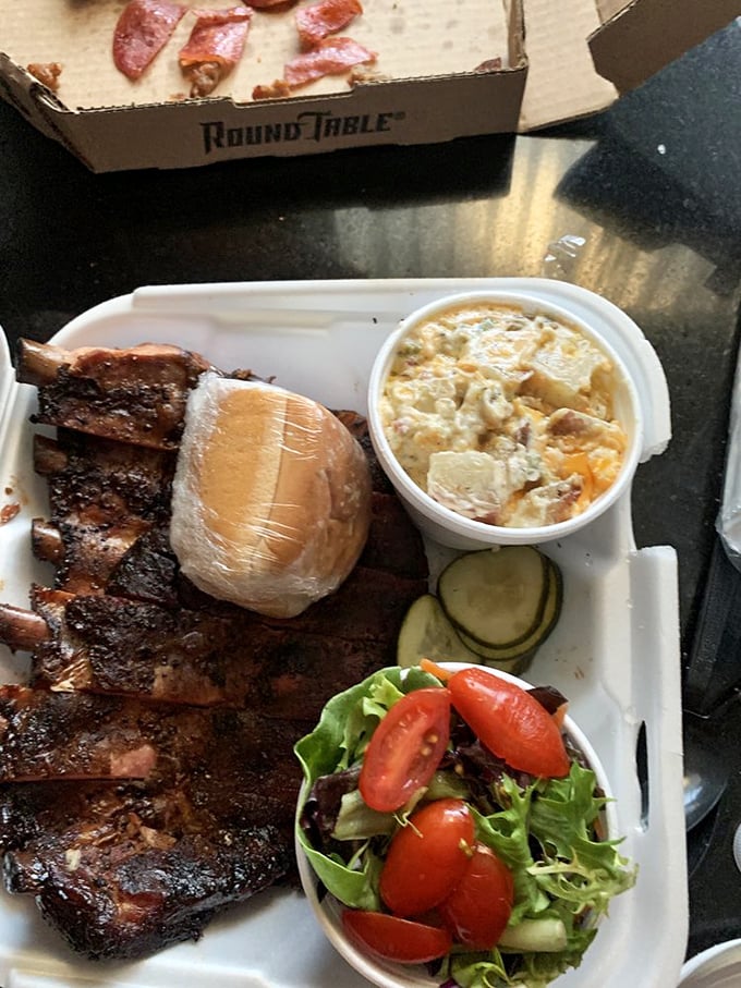 The pulled pork sandwich arrives like a meaty mountain, flanked by potato salad and mac & cheese that refuse to be mere sidekicks.