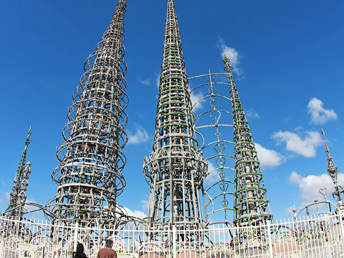 Spindly towers reach for the sky, adorned with broken pottery and bottles – one man's vision transformed into an architectural marvel.